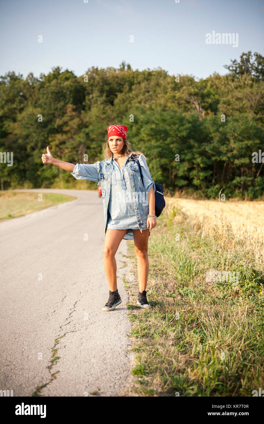young woman hitchhiking on a country road Stock Photo - Alamy