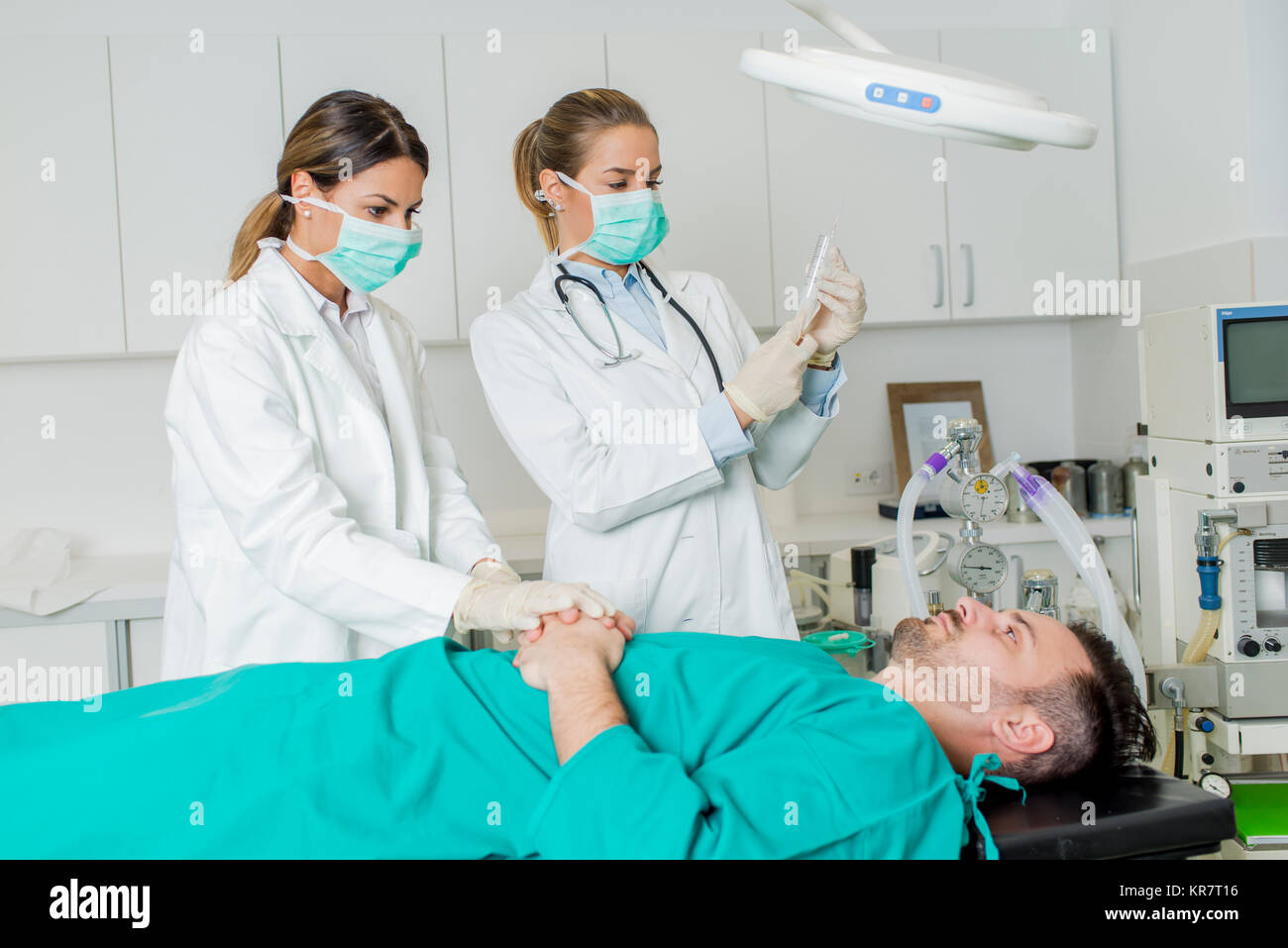 Female doctors preparing male patient for intervention in the hospital ...