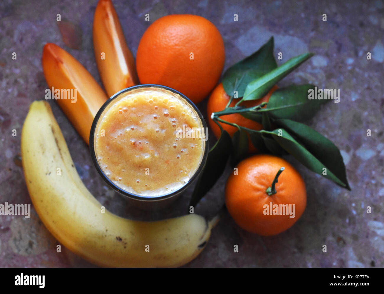 still life of smoothie glass with persimmon, banana, mandarins on the ...