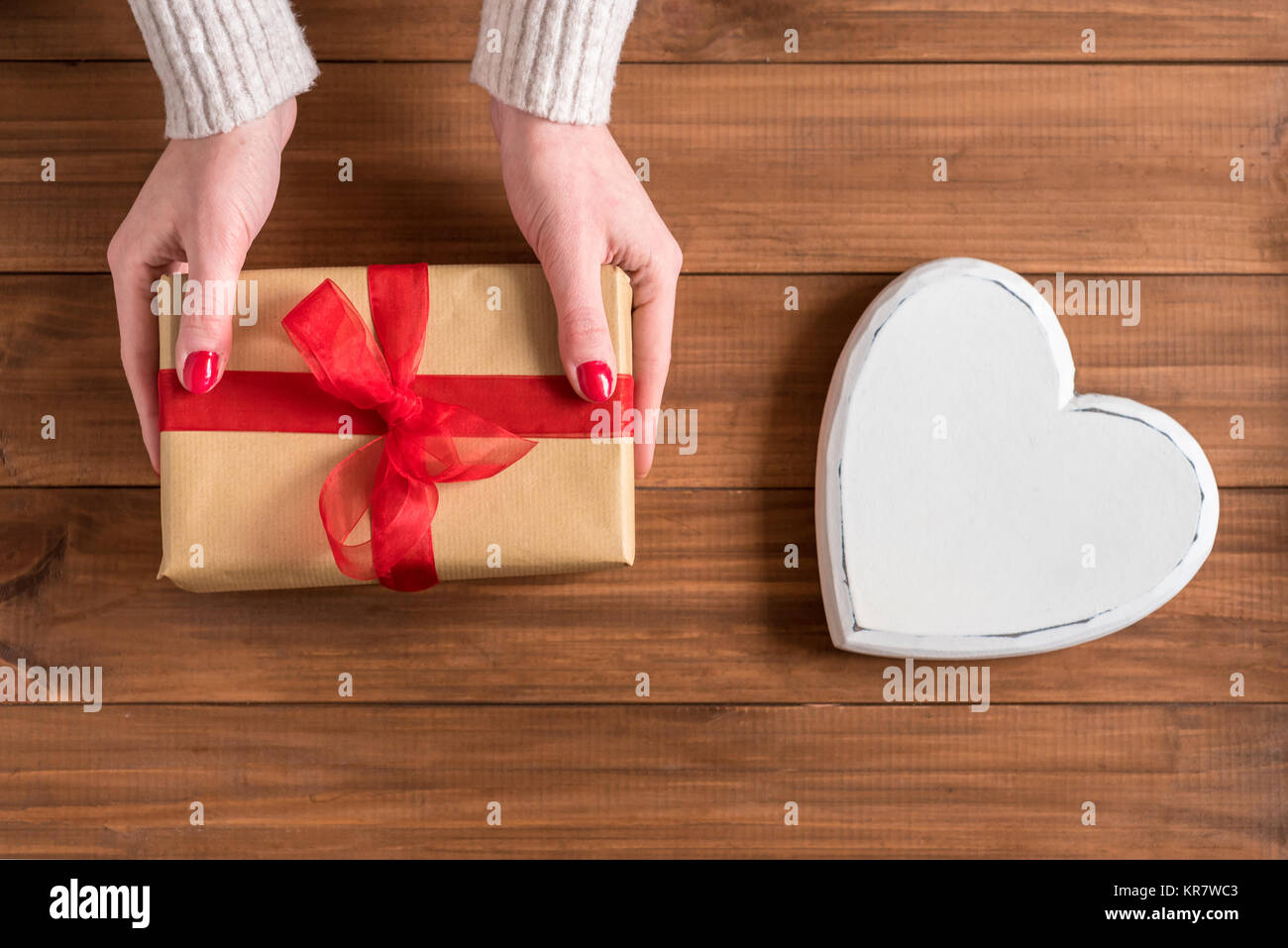 Female hands giving gift on wooden background Stock Photo - Alamy