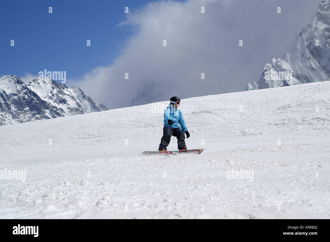 Snowboarder downhill on ski slope in high snowy mountains at sun winter ...