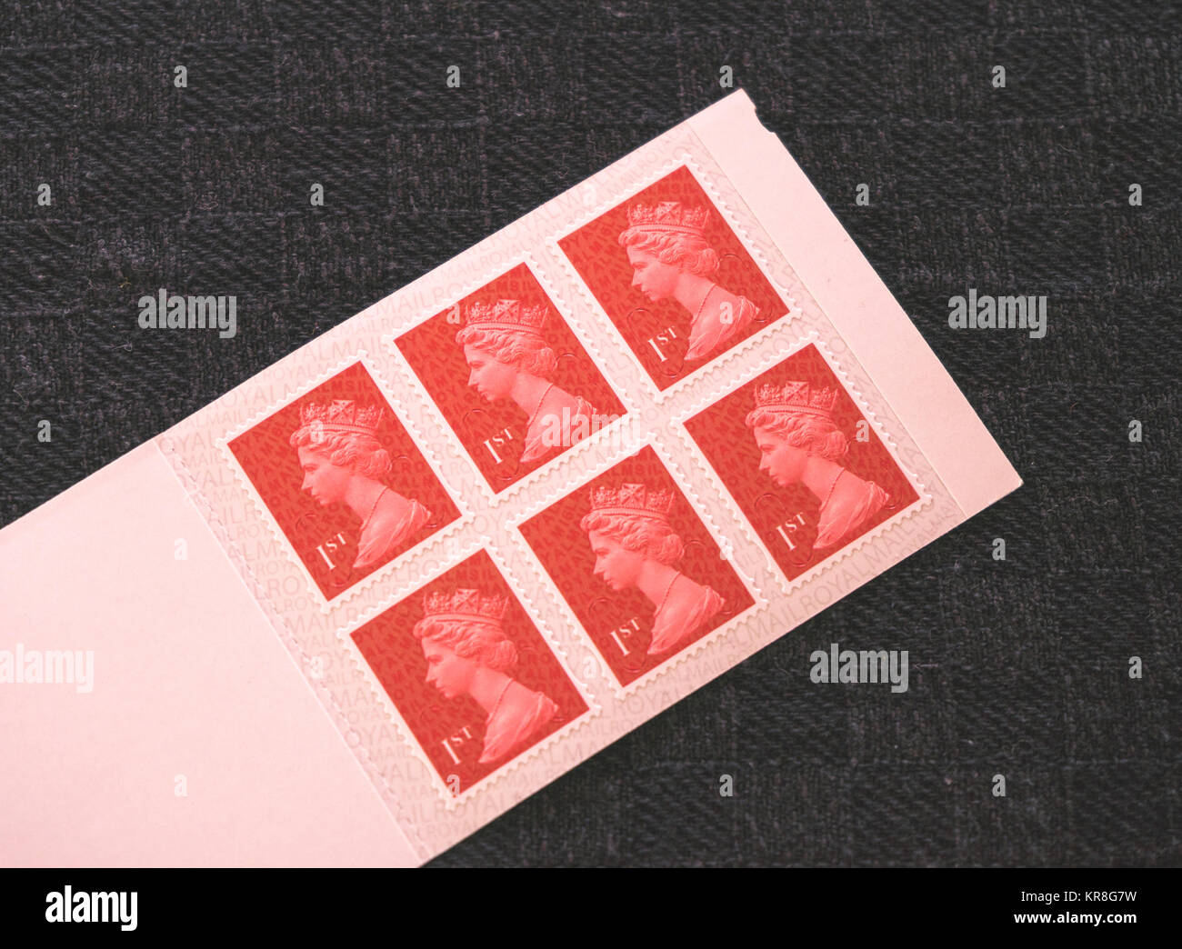 A set of six red Royal Mail First Class stamps against black background ...