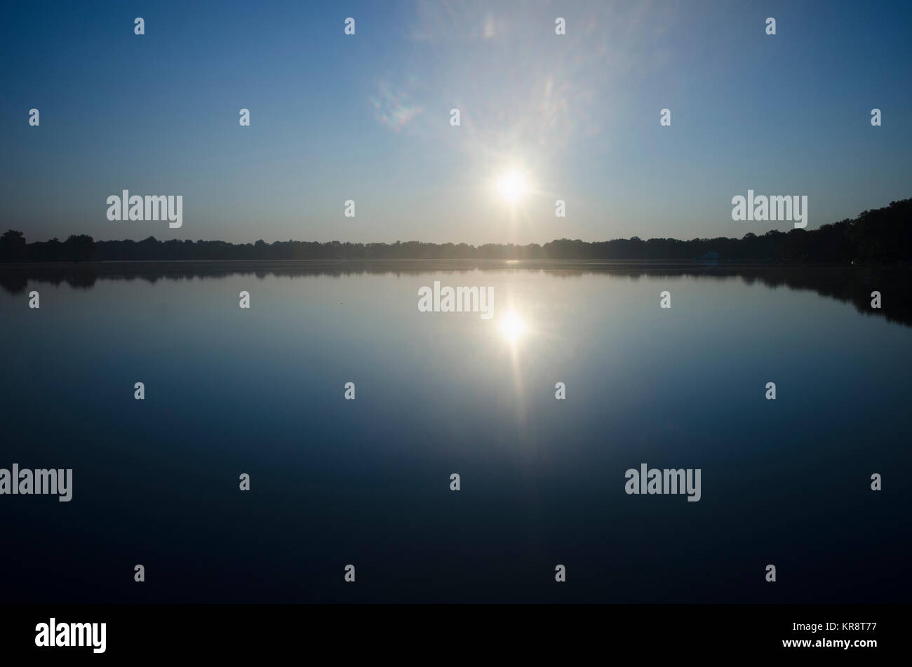 Sun rising above lake Stock Photo - Alamy