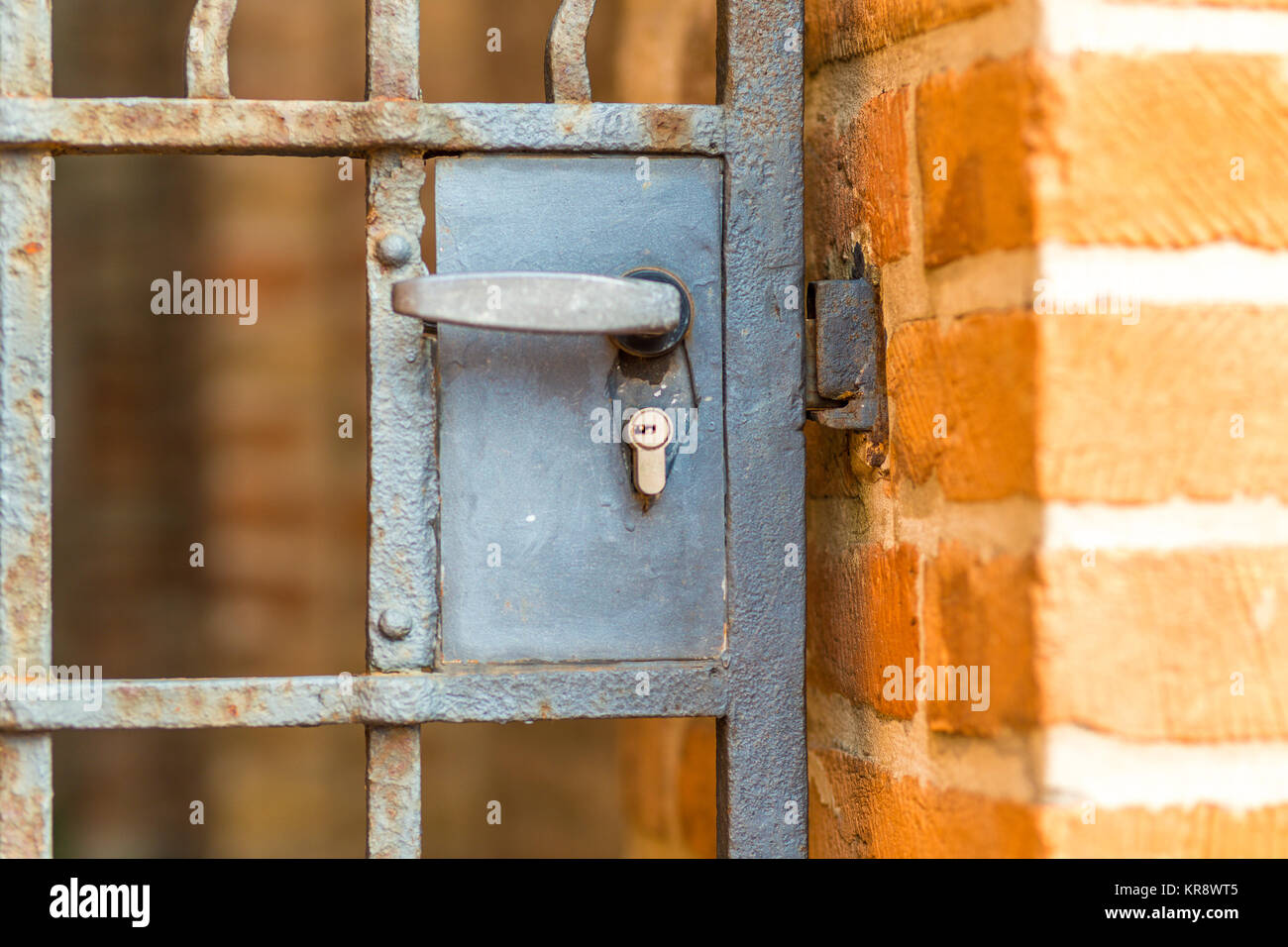 Lock with handle in old door with rusty iron grate on brick wall Stock ...