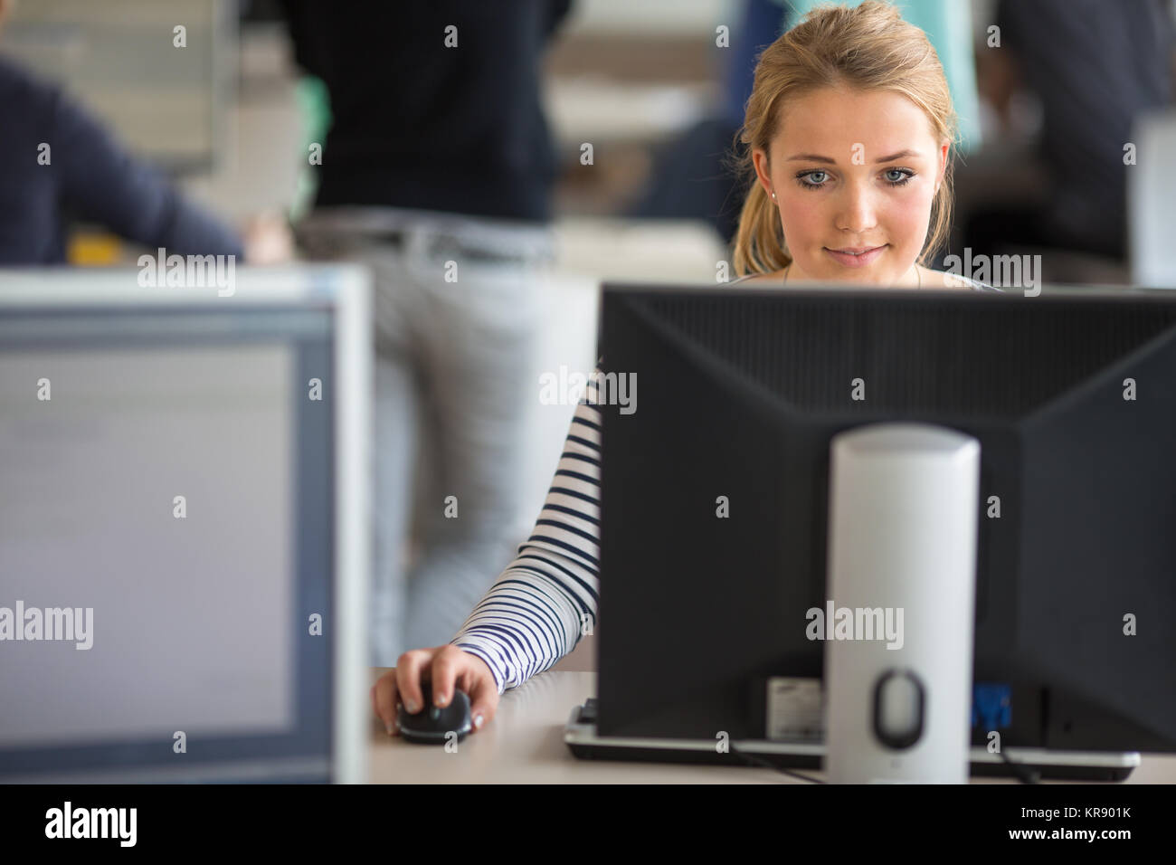 Pretty, female student looking at a desktop computer screen, learning ...