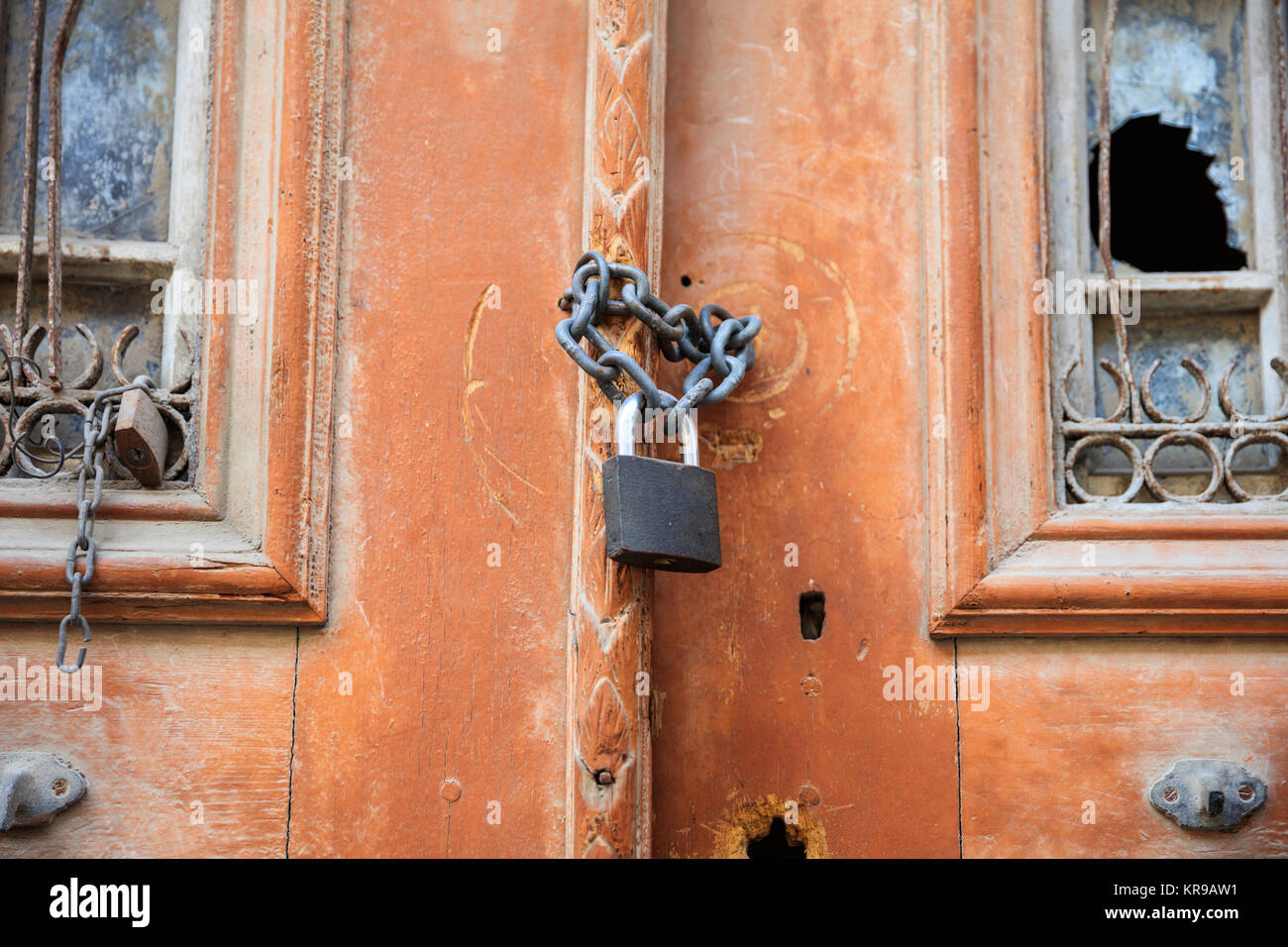 Rusty lock on a destroyed wooden entrance with broken window. Close up ...