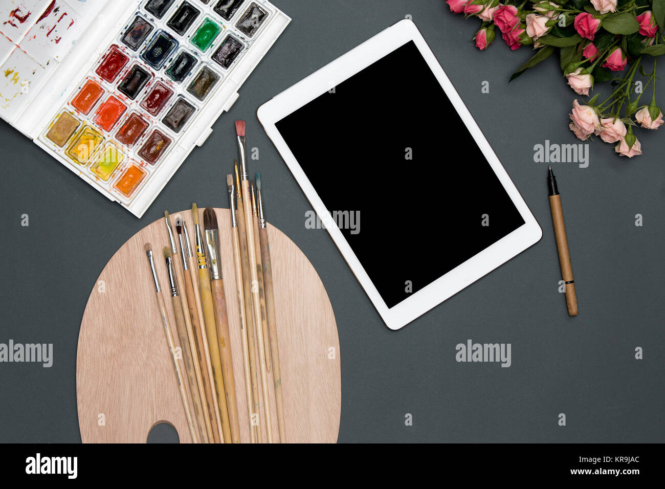 The workspace of artist with laptop, paints, paintbrushes, flowers on ...