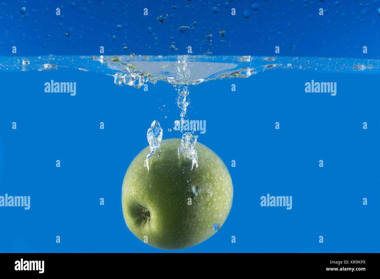 Fresh apple falling in water splash on blue background Stock Photo - Alamy