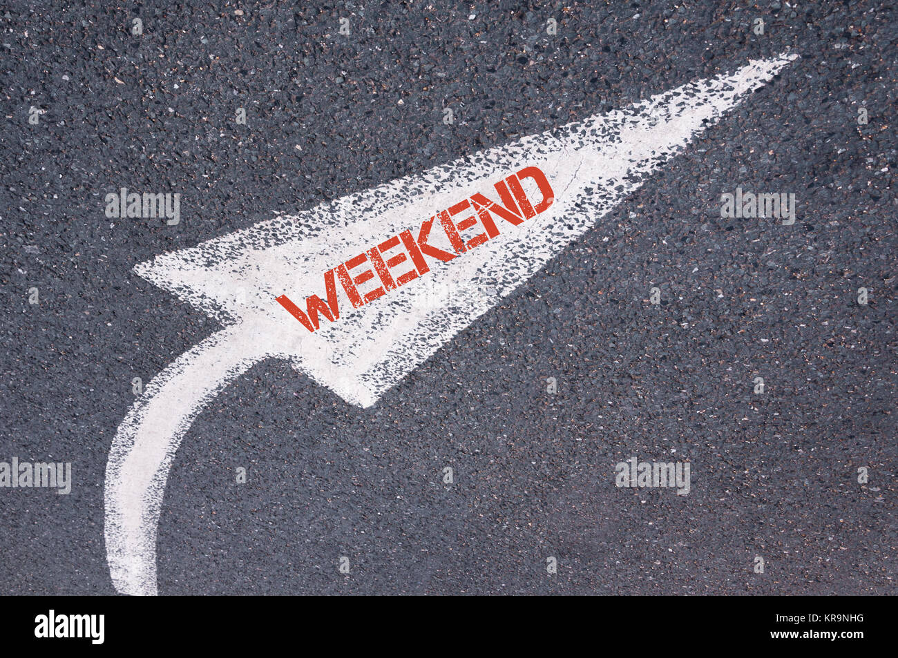 Directional white painted arrow with word WEEKEND over road surface ...