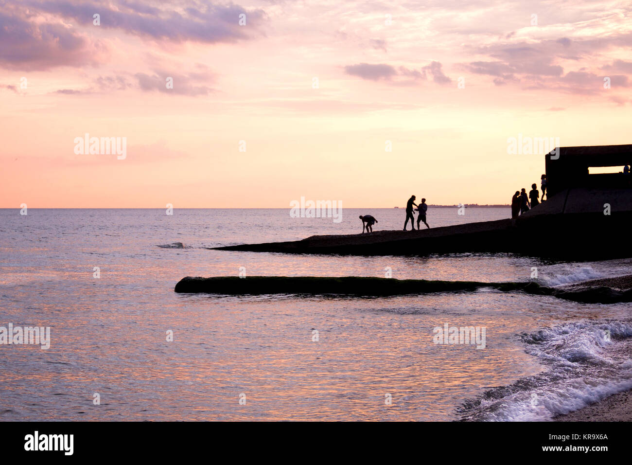 Sea jetty at sunset on brighton beach, the jetty is silhoutted black by ...