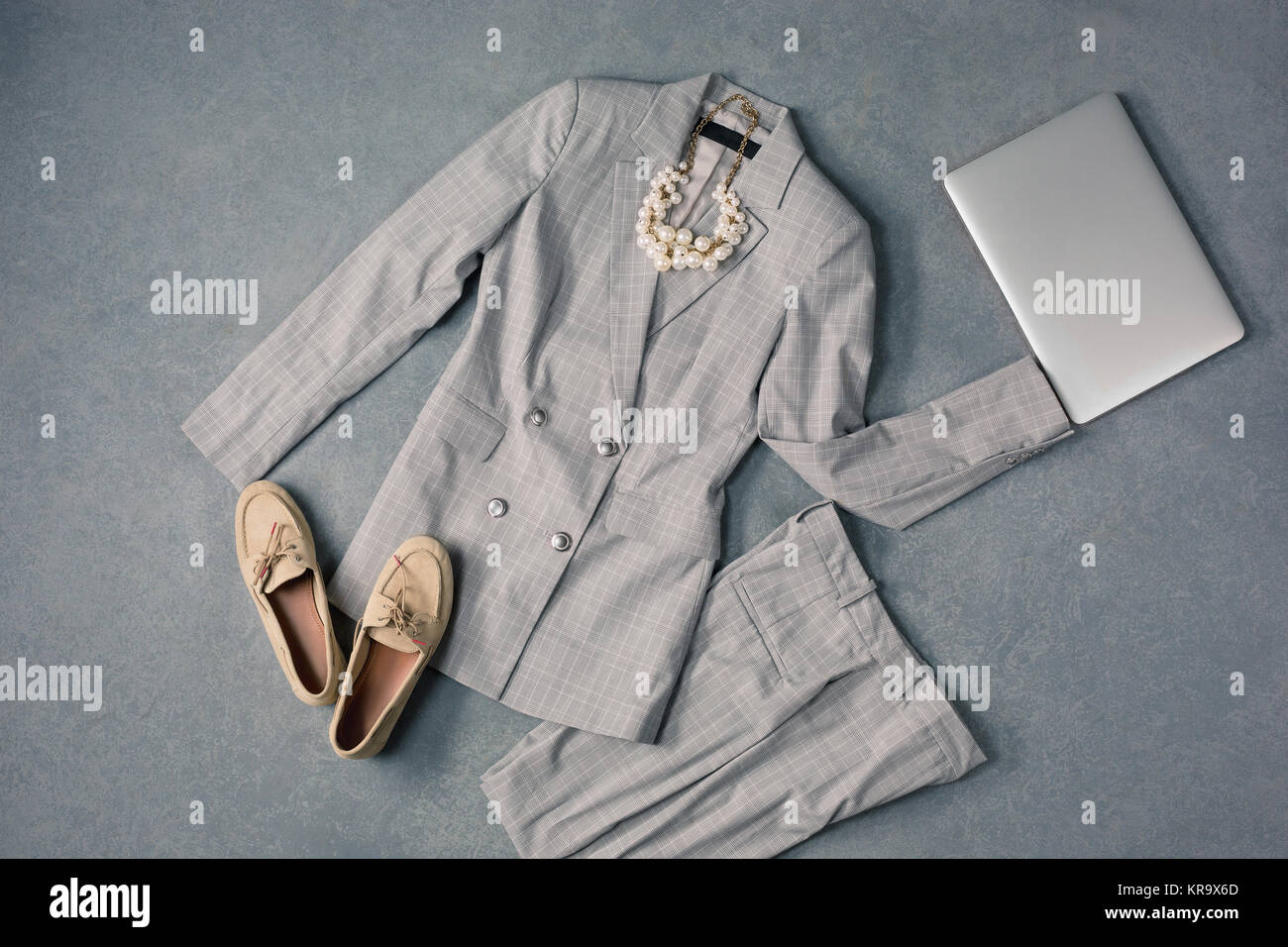 The top view of collection of elegant female clothes on gray - suit ...
