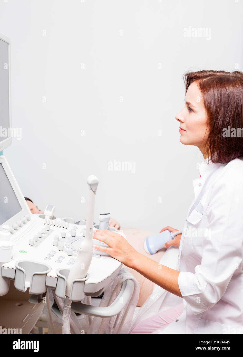 Sonographer scanning young pregnant woman's belly with ultrasonic ...