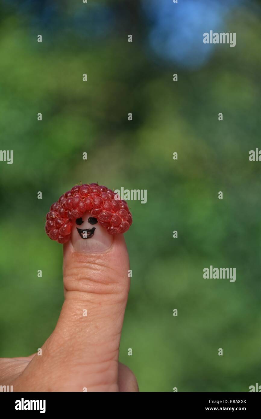 thumb with raspberry and a smiling face Stock Photo - Alamy