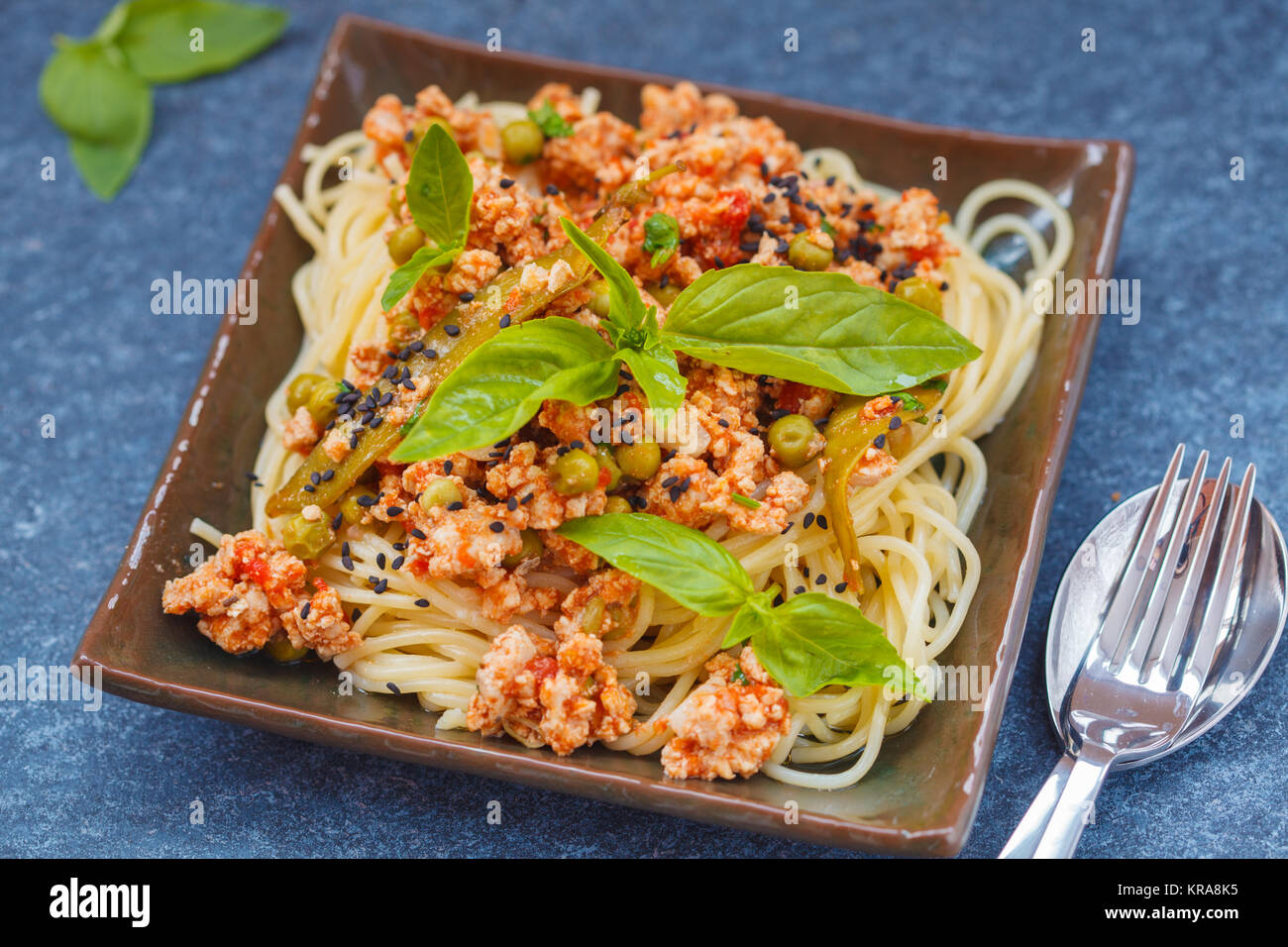 Homemade pasta with chicken forcemeat, green peas and basil in a square ...