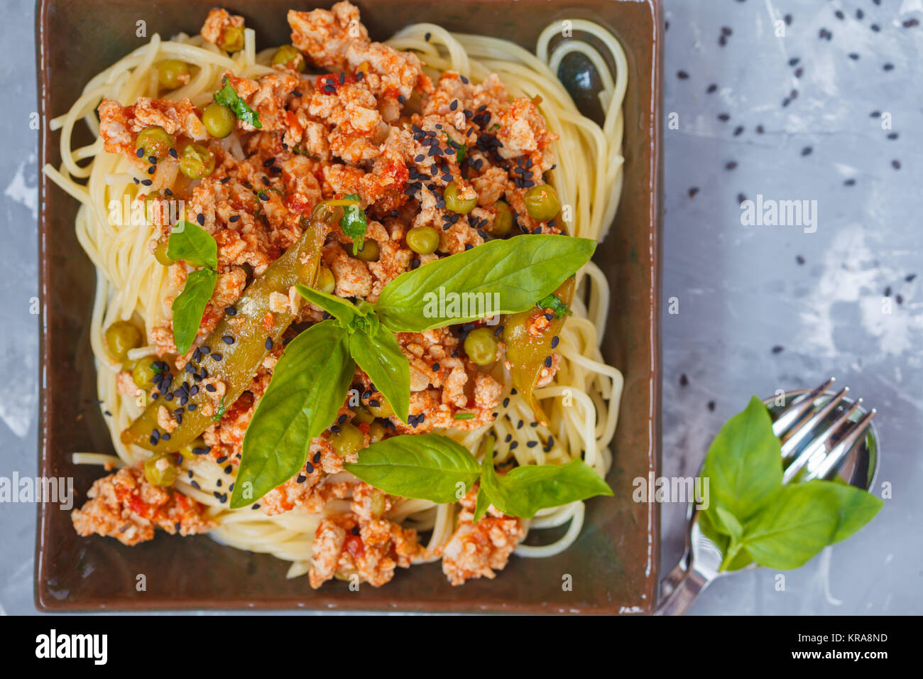 Homemade pasta with chicken forcemeat, green peas and basil in a square ...