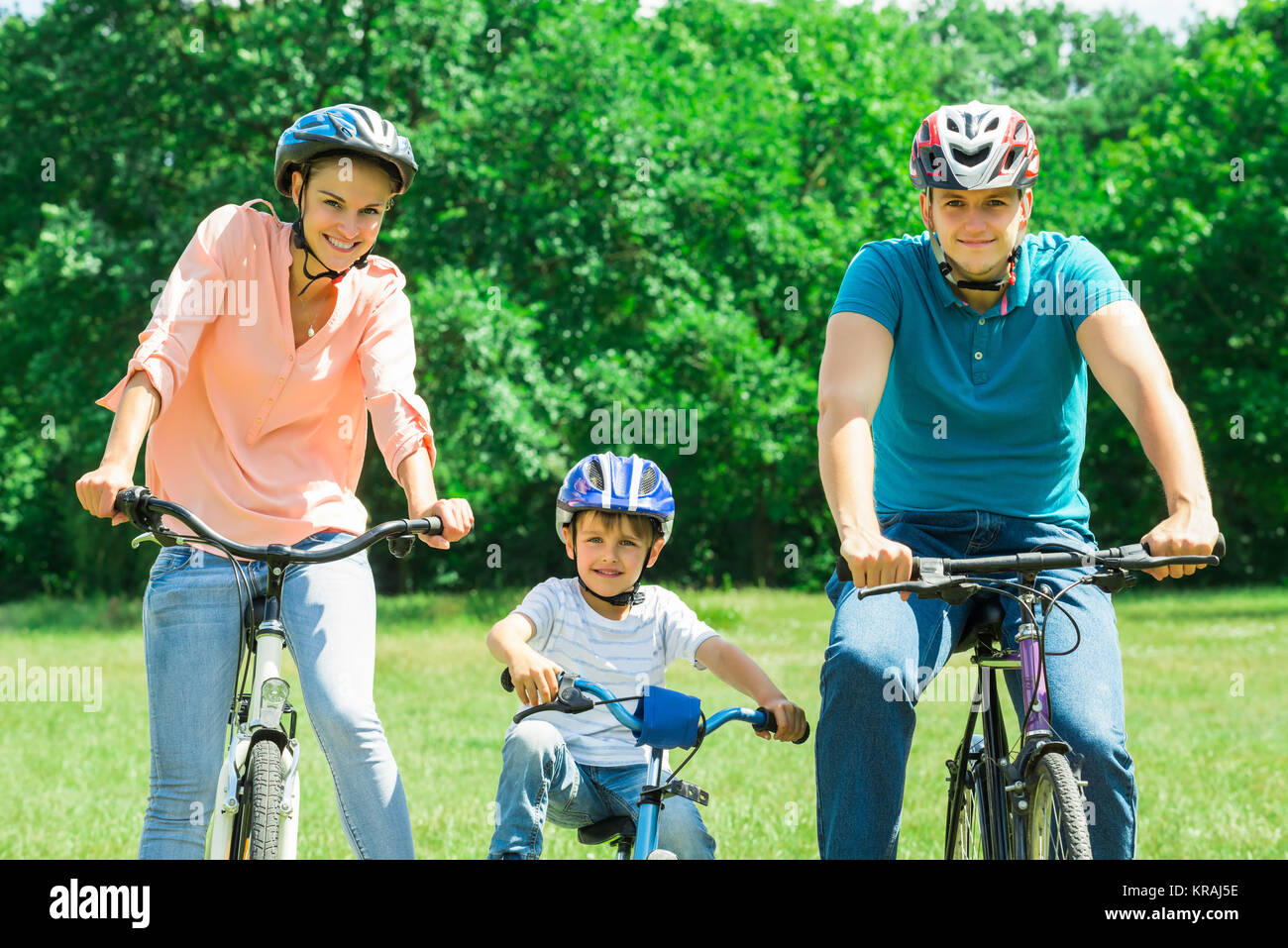 Happy Family Cycling In Park Stock Photo - Alamy