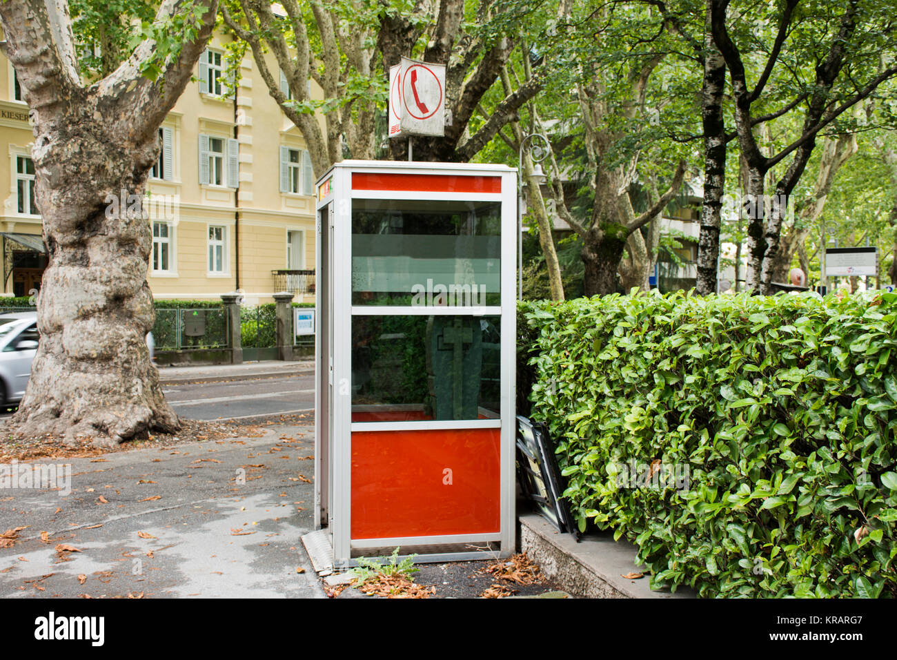 Public telephone on pathway beside traffic road in small alley for ...