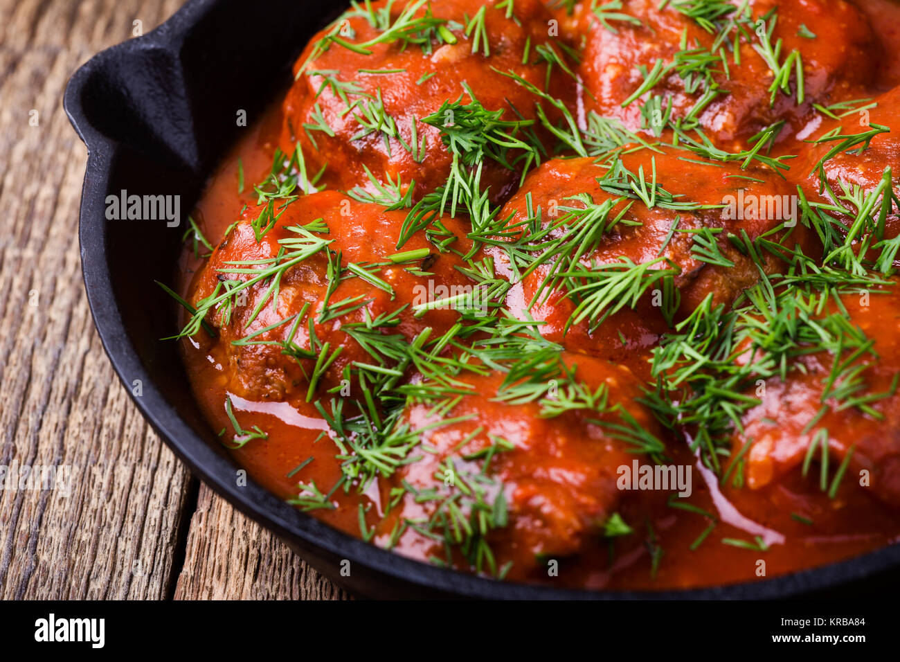Beef meatballs in cast iron skillet with tomato sauce served with fresh ...