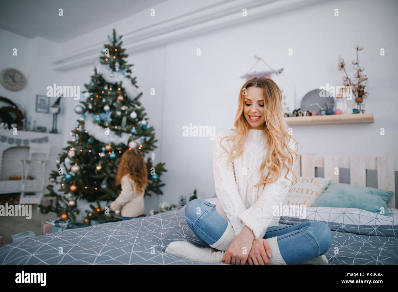 pretty blonde woman sitting on the bed Stock Photo - Alamy