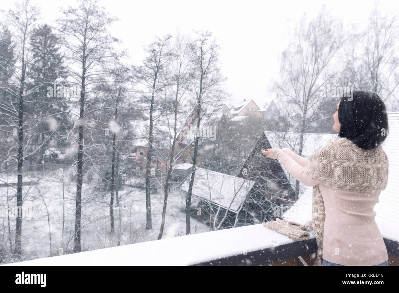 Young brunette woman, dressed casual, stands on a balcony with her ...