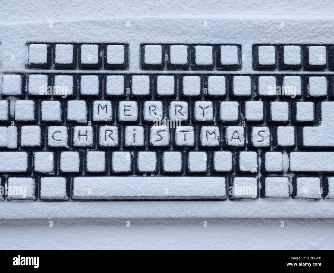 computer keyboard covered with white snow with inscription merry ...