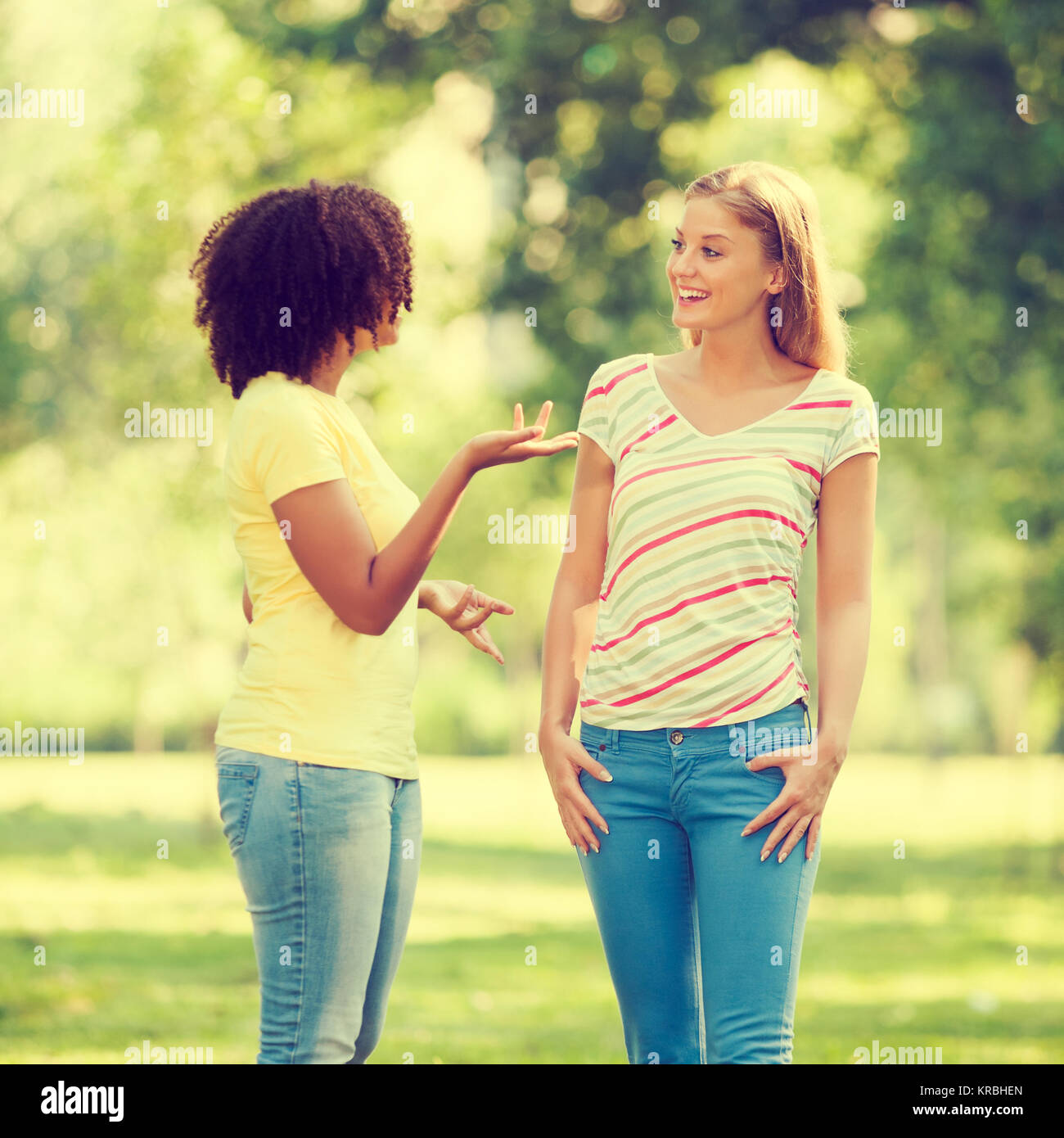 Two young women talking in park Stock Photo - Alamy