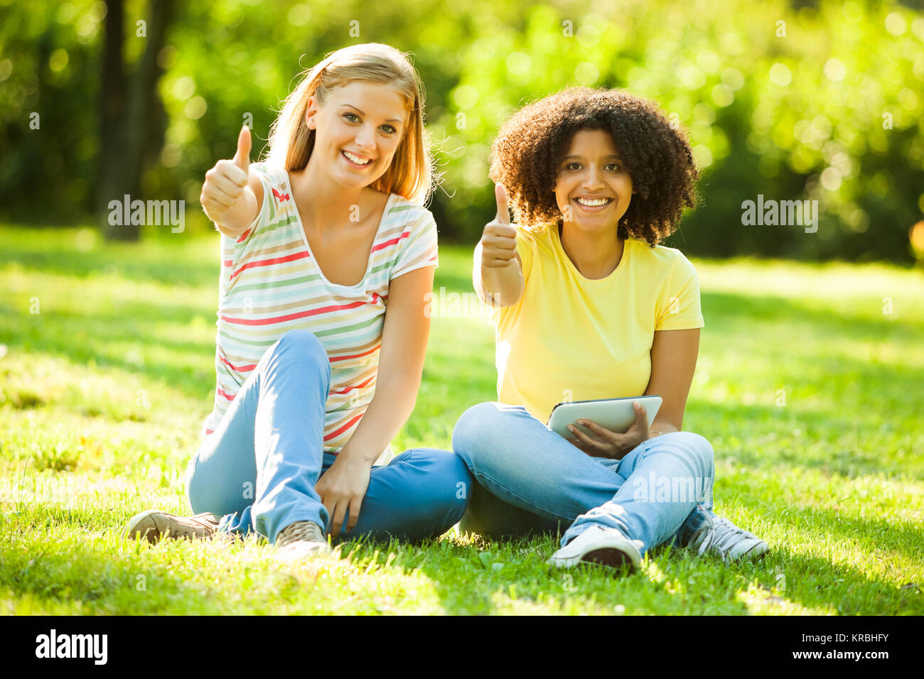Two young women using tablet in park Stock Photo - Alamy