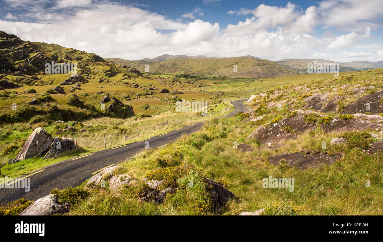 A narrow mountain pass road winds through rocky moorland climbing to ...