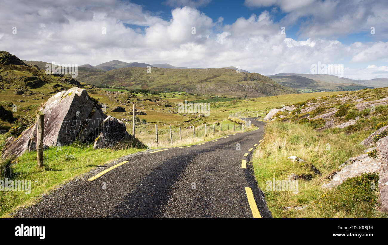 A narrow mountain pass road winds through rocky moorland climbing to ...