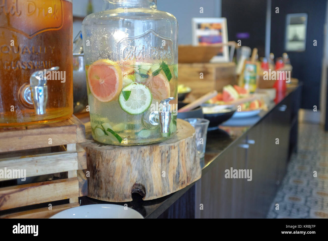 A jug of water with citrus fruit and cucumber in it on table serving a ...