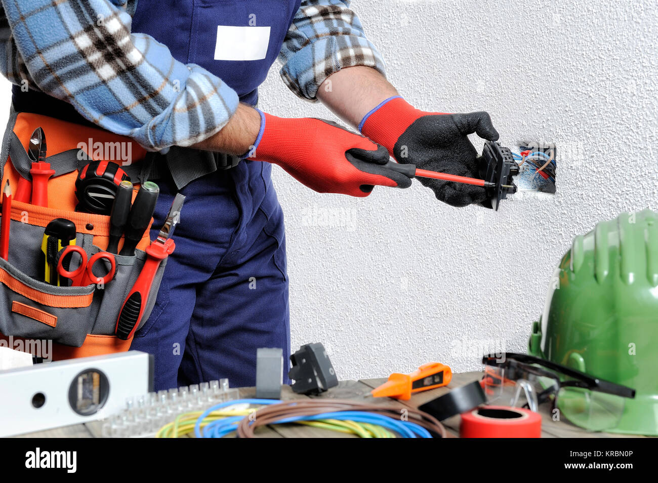 Electrician with hands protected by gloves and insulated tools works on ...