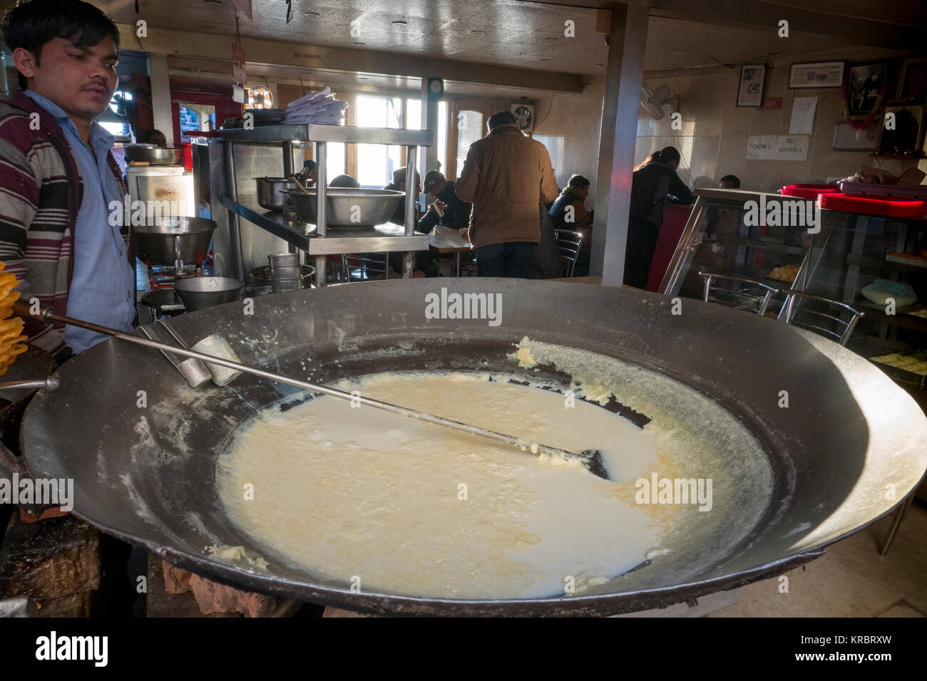Man heating up milk in large pan at eating place in Shimla, Himachal ...