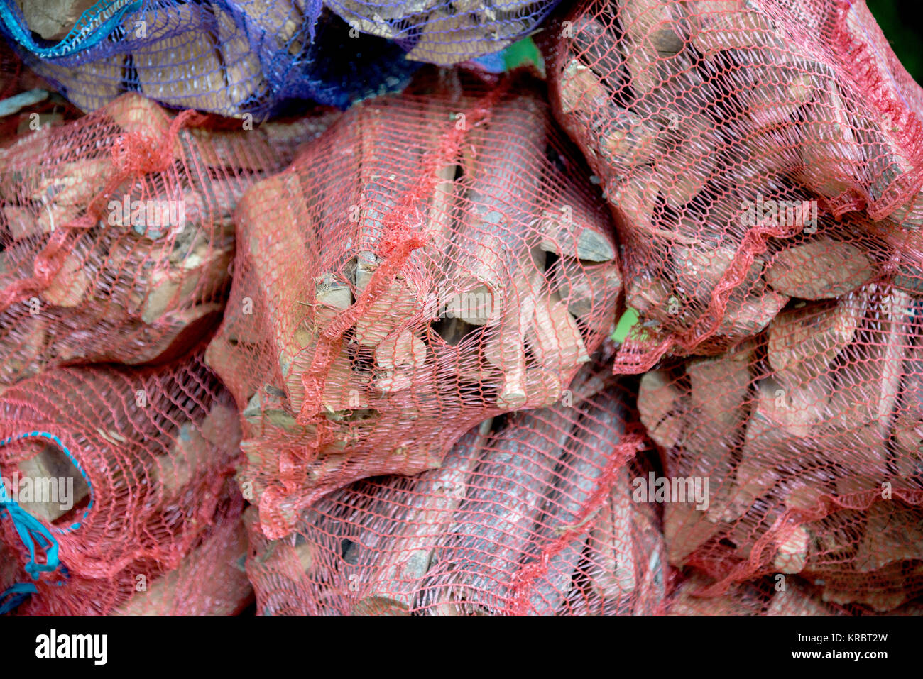 Firewood in net bag sold in the store Stock Photo - Alamy