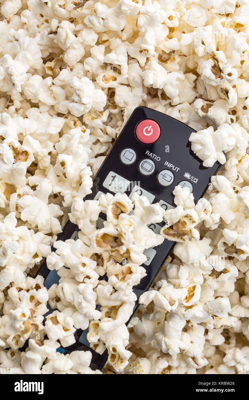 Tasty popcorn and tv remote control Stock Photo - Alamy