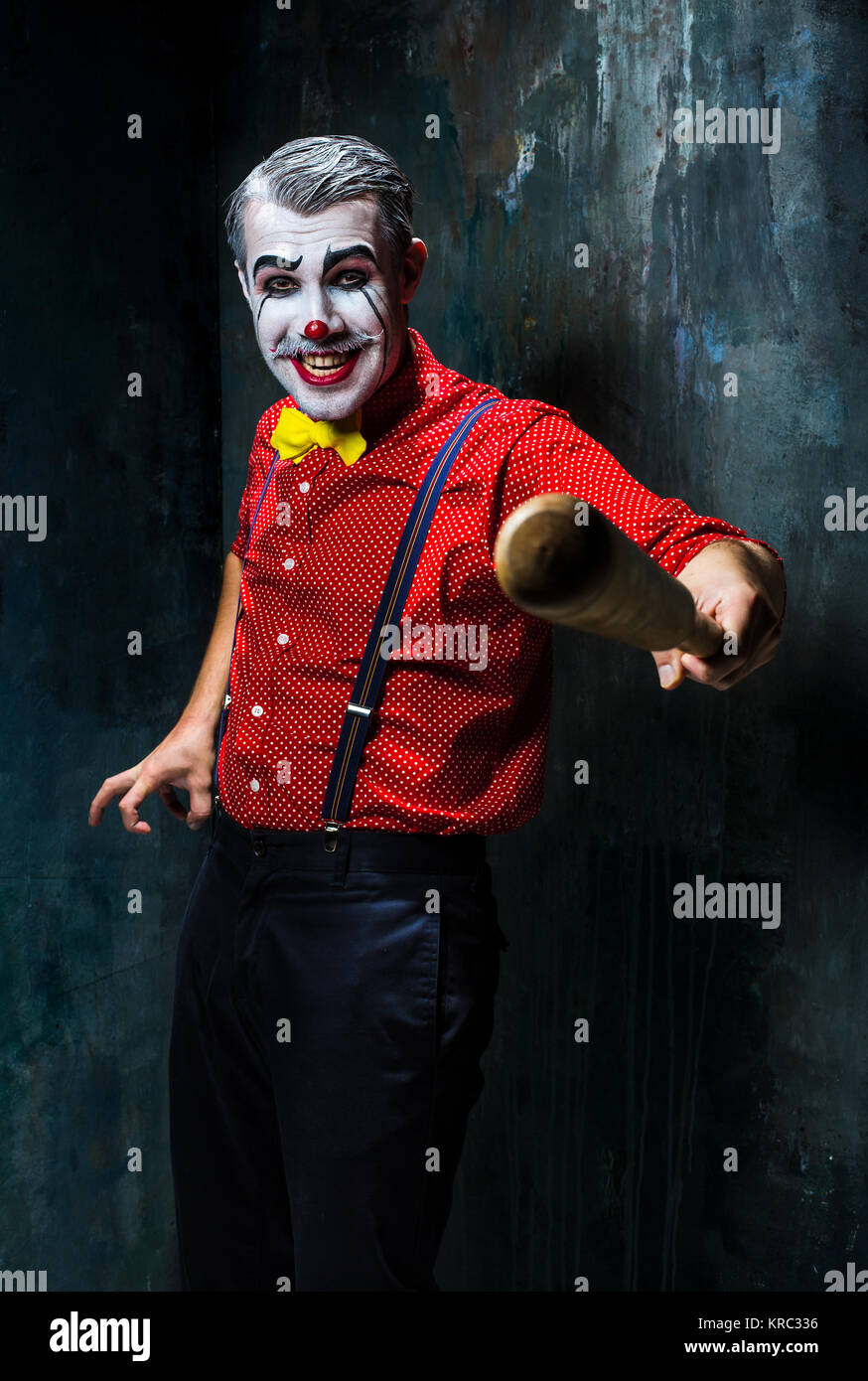 The scary clown and baseball-bat on dack background. Halloween concept ...