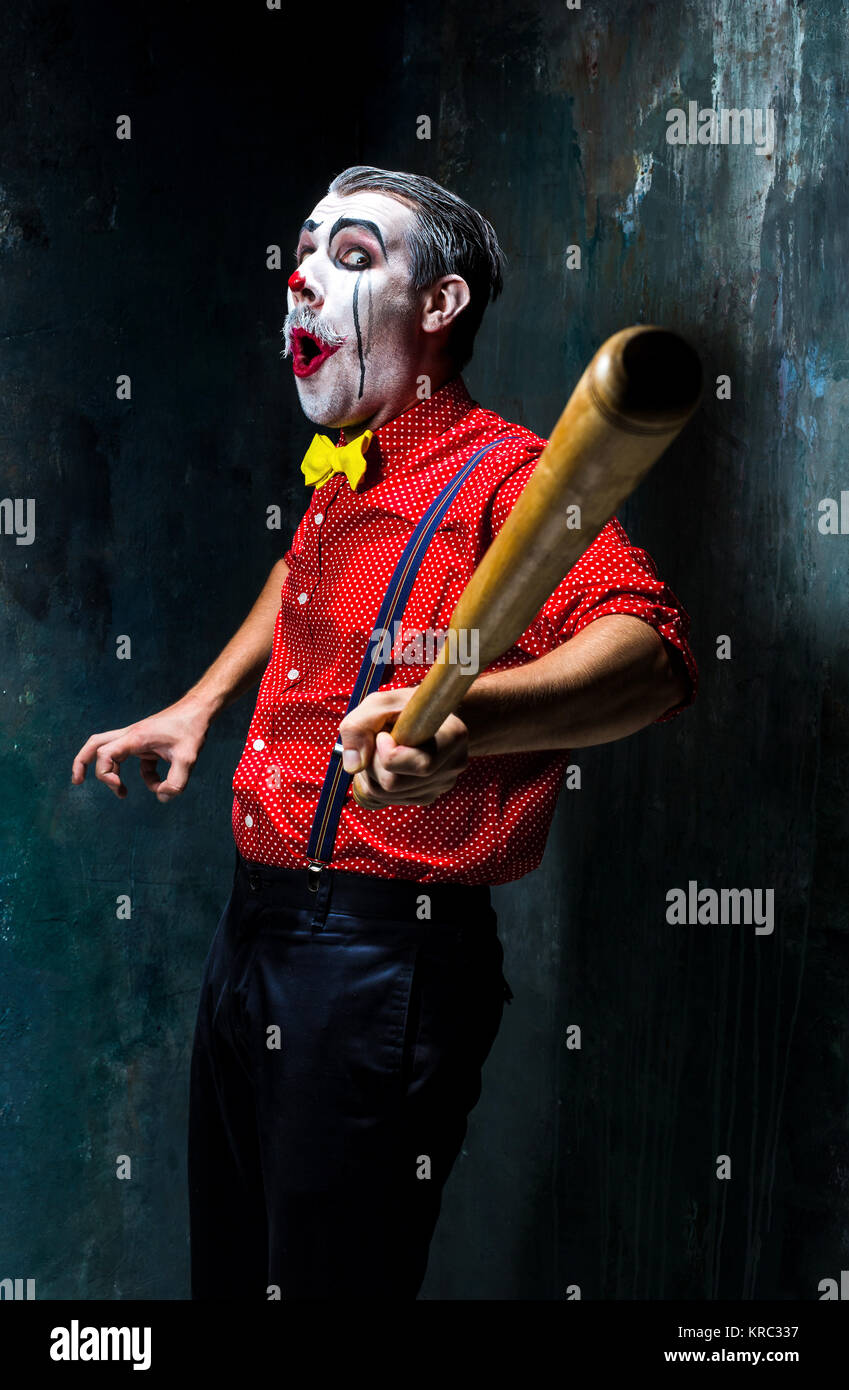The scary clown and baseball-bat on dack background. Halloween concept ...