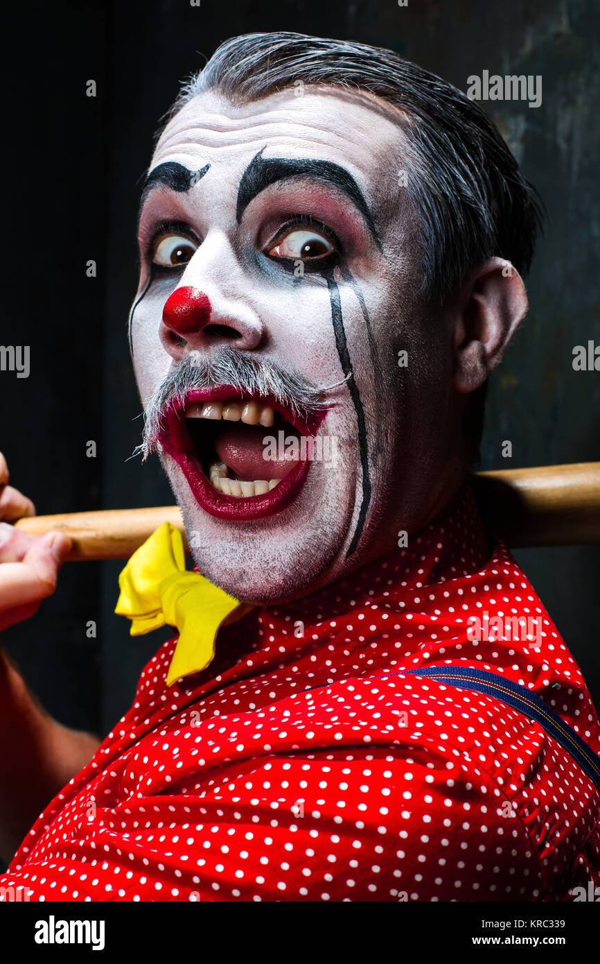 The scary clown and baseball-bat on dack background. Halloween concept ...
