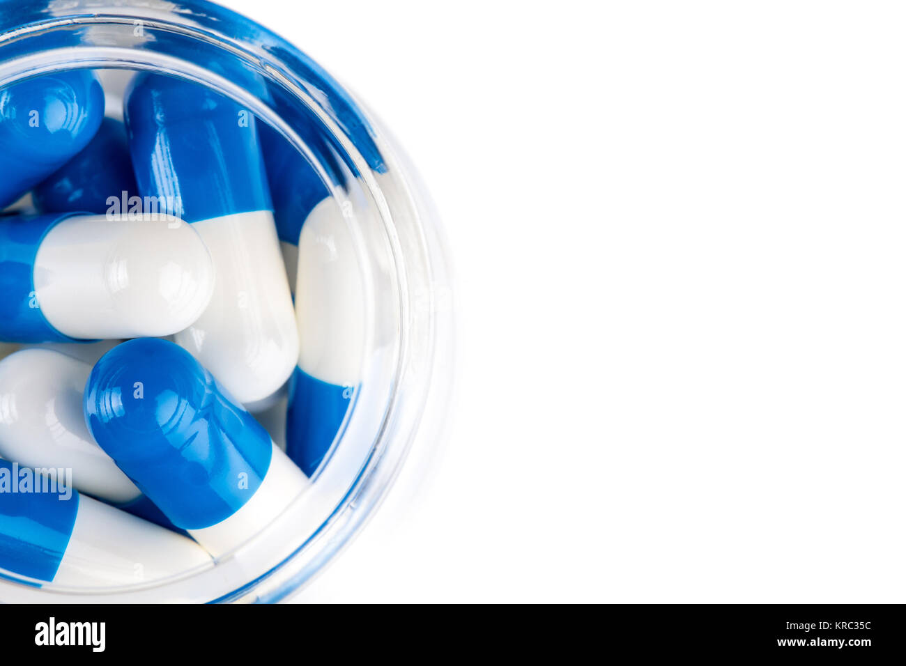 Blue white capsules in clear glass container top view Stock Photo - Alamy