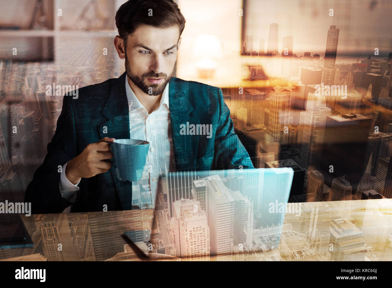Handsome businessman drinking coffee while reading from laptop Stock ...