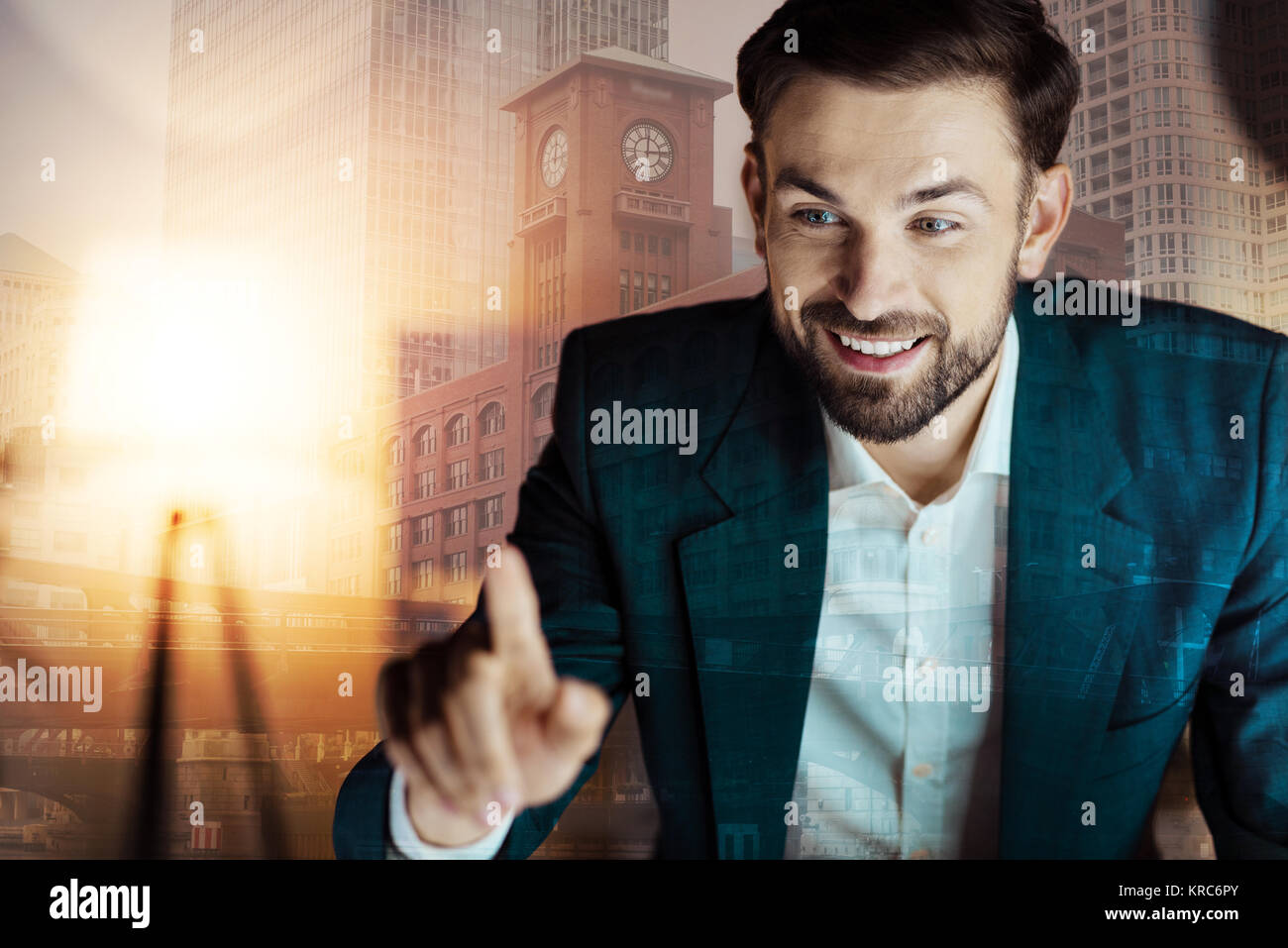 Smiling man raising his finger trying to touch something Stock Photo ...