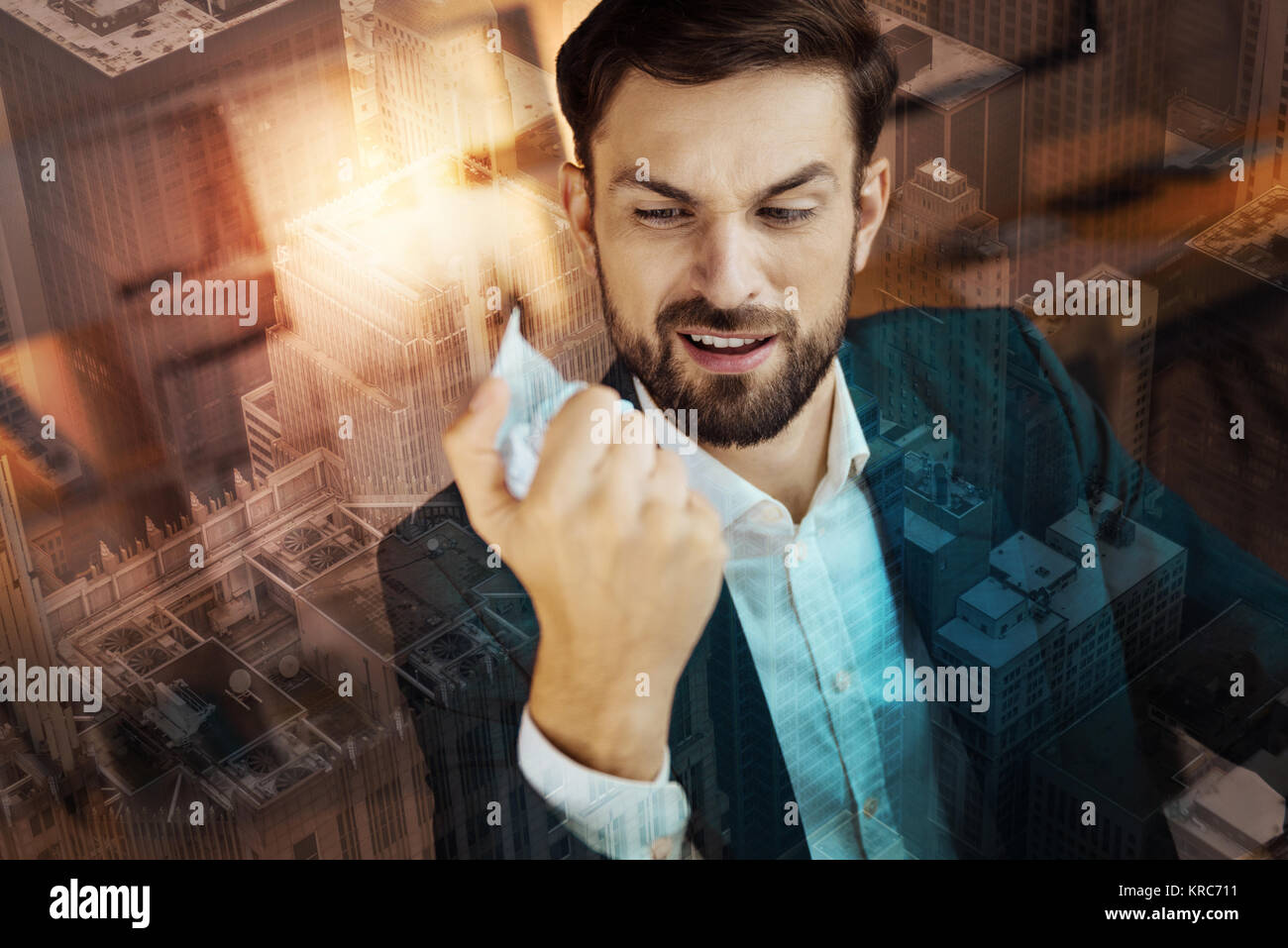 Irritated man in suit squeezing paper in his hands Stock Photo - Alamy