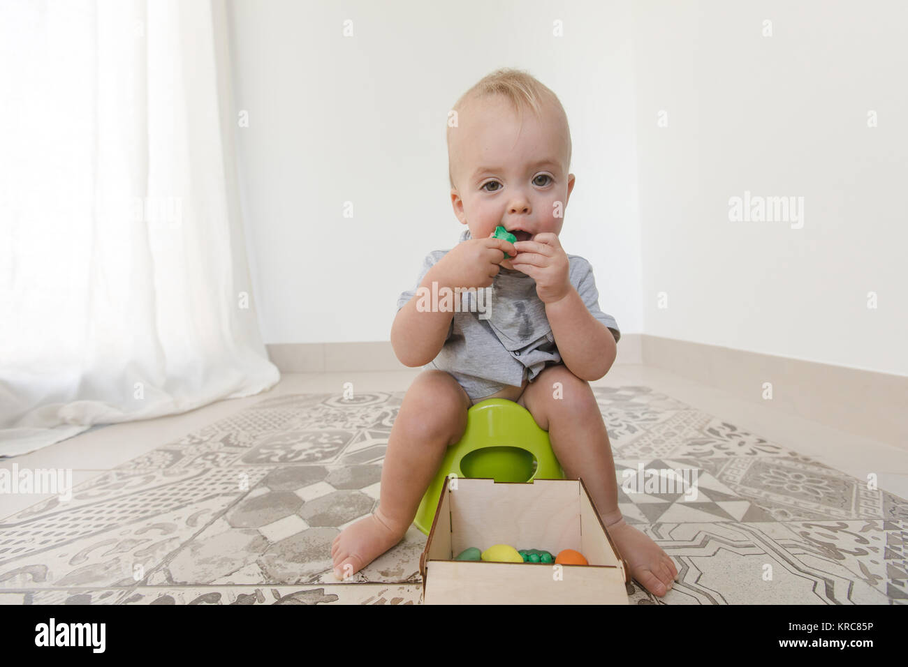 Baby sitting on potty and eating vegetables Stock Photo - Alamy