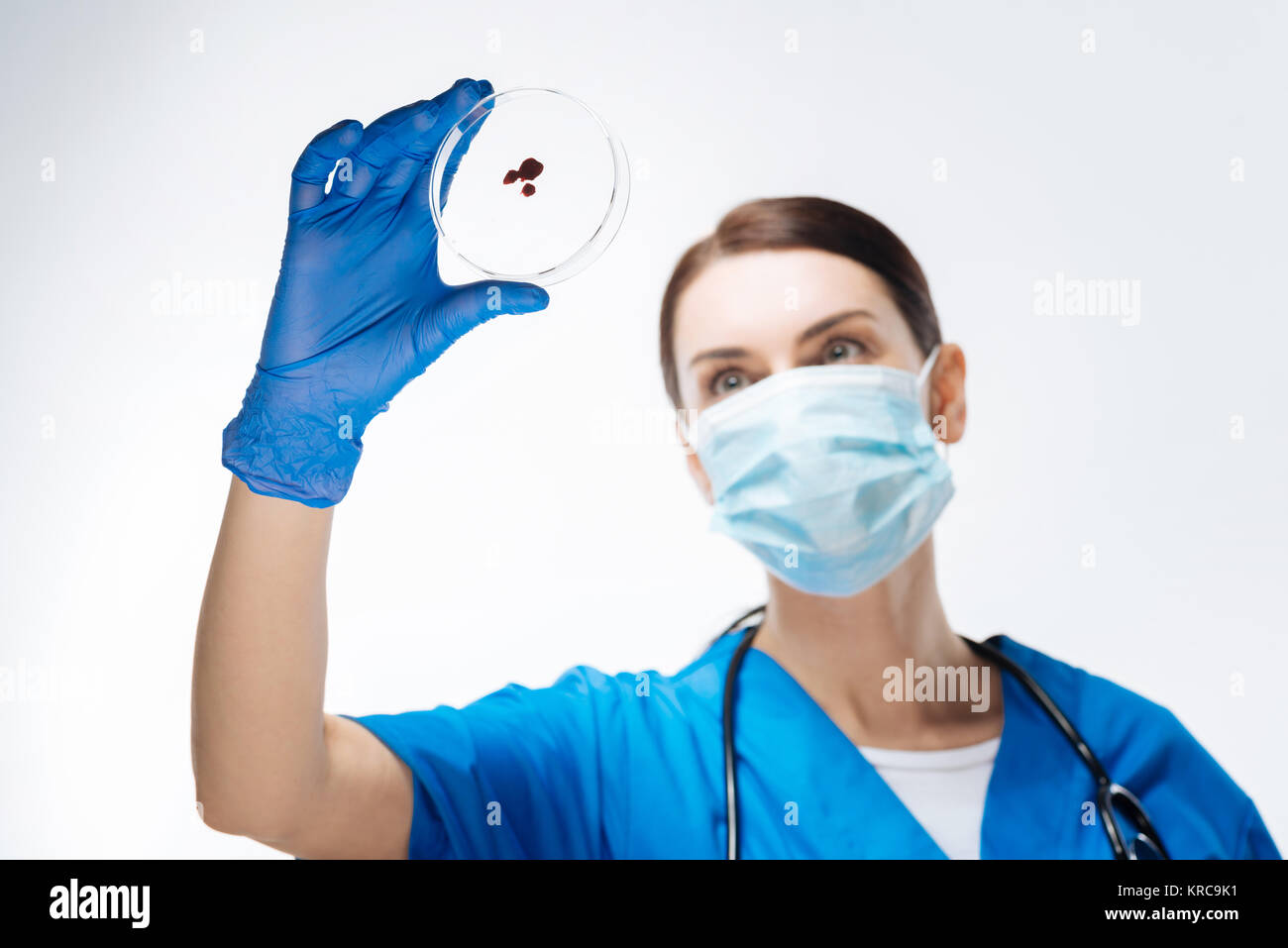 Professional female lab assistant examining blood sample Stock Photo ...