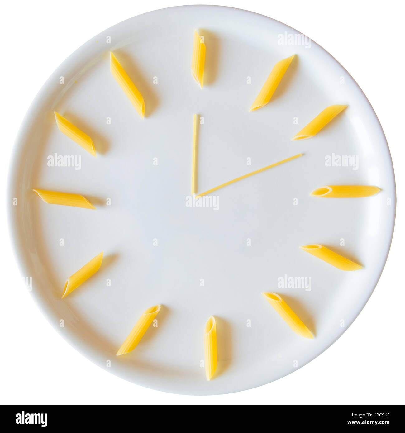 Uncooked italian pasta penne in clock shape on dish on white background ...