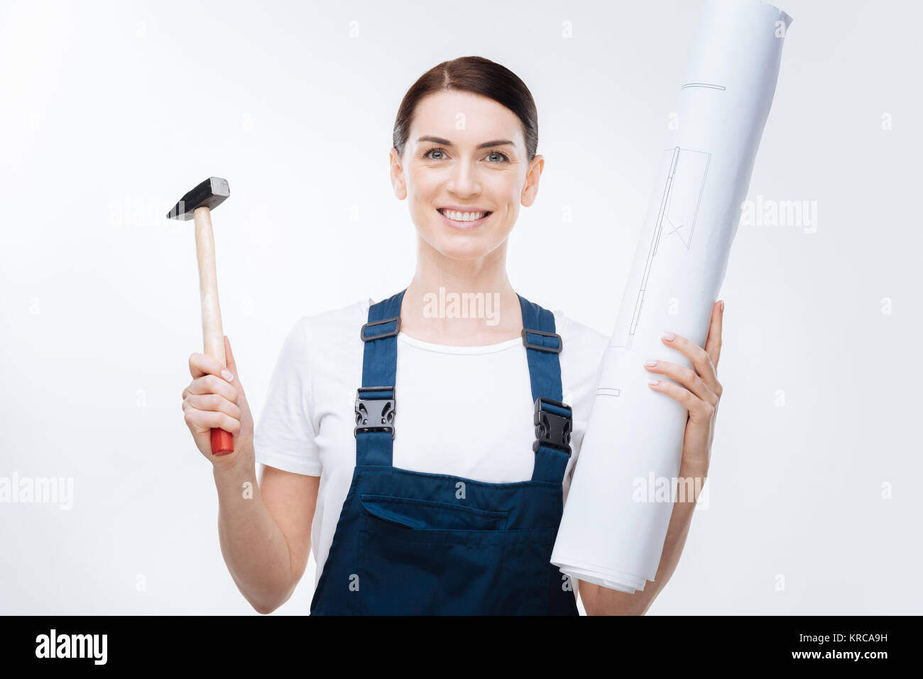 Charming female worker building new with hammer Stock Photo - Alamy