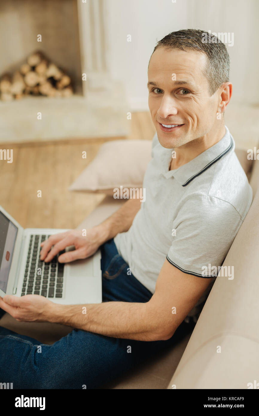 Attractive young man smiling and holding a modern laptop Stock Photo ...