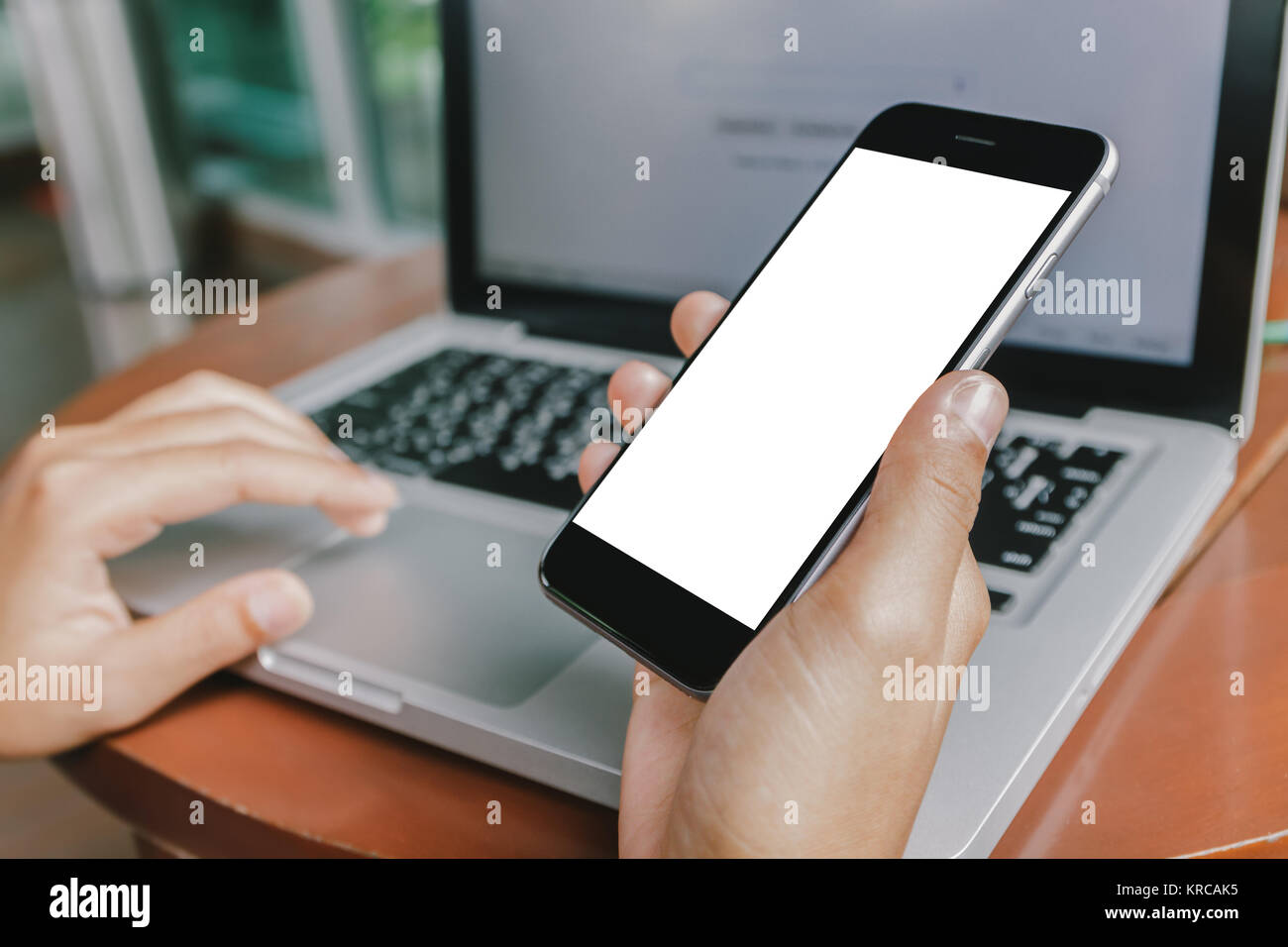 hand holding phone and using laptop computer in coffee shop Stock Photo ...
