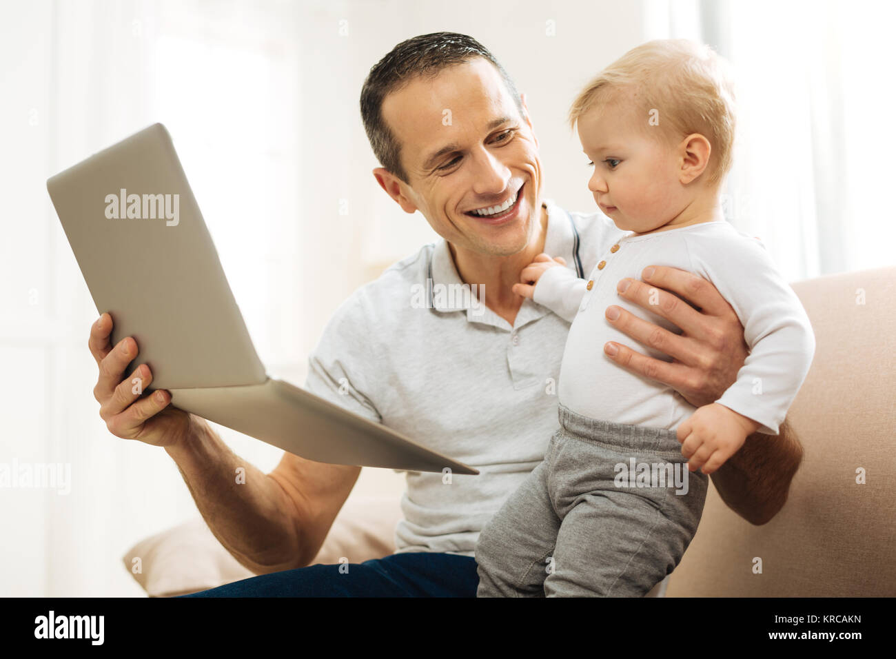 Kind attentive father showing a funny cartoon to his child and smiling ...