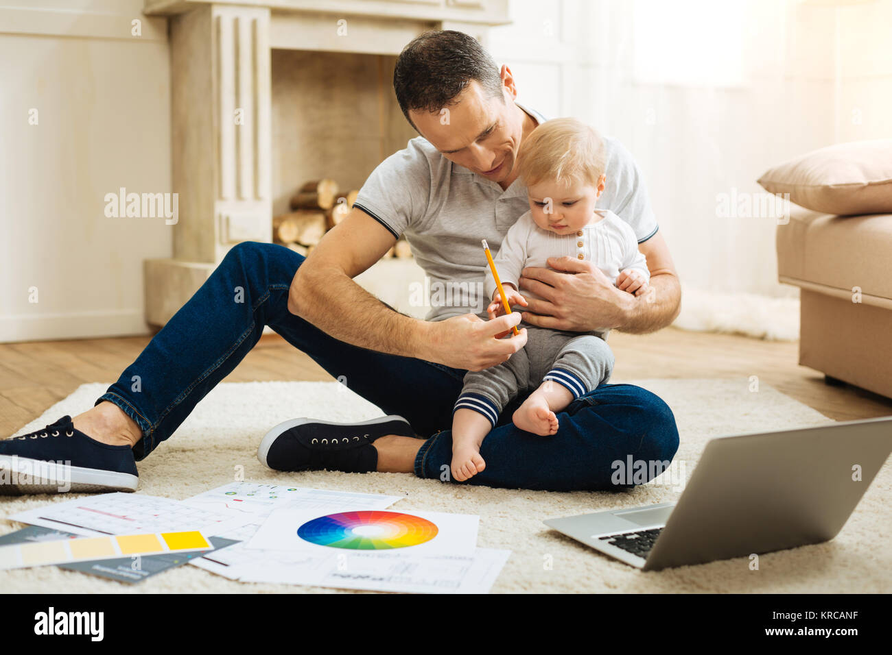 Calm responsible father showing his child a pencil and talking to him ...