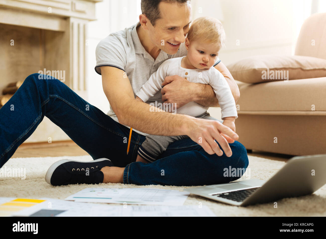 Cheerful attentive father pointing to the screen while showing a ...